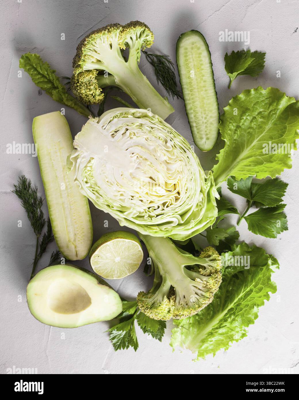 Composition of fresh green cut in half vegetables on a white background ...