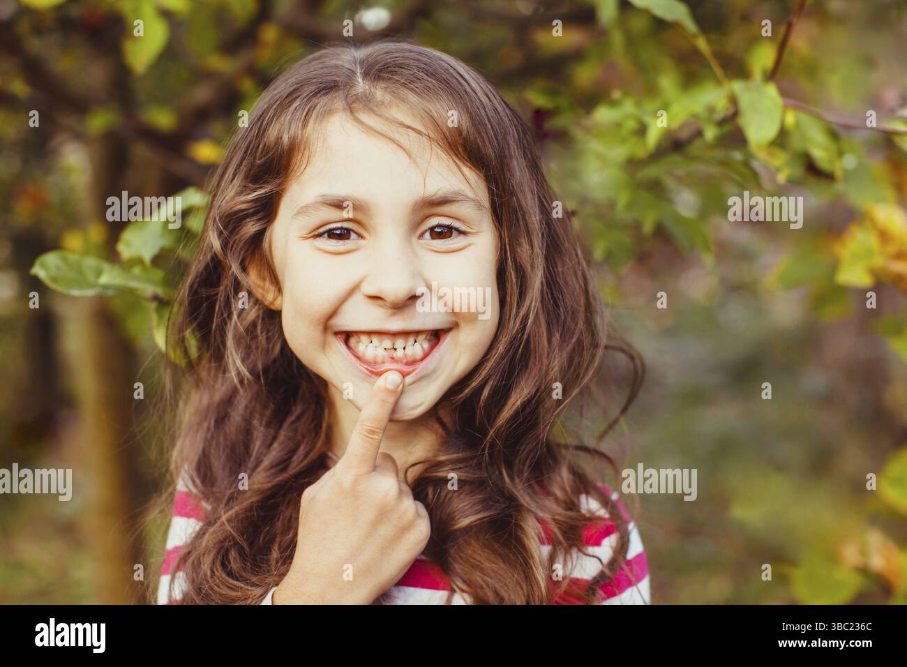 Beautiful child girl with long curly brown hair and brown eyes pointing ...