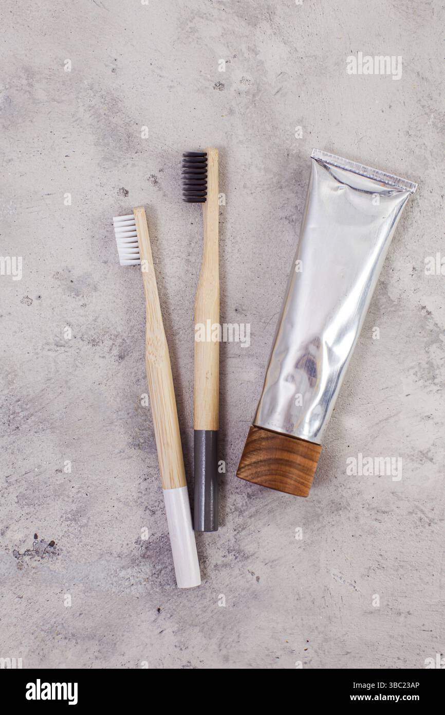 Bamboo teeth brushes and tube of toothpaste on minimalistic concrete ...