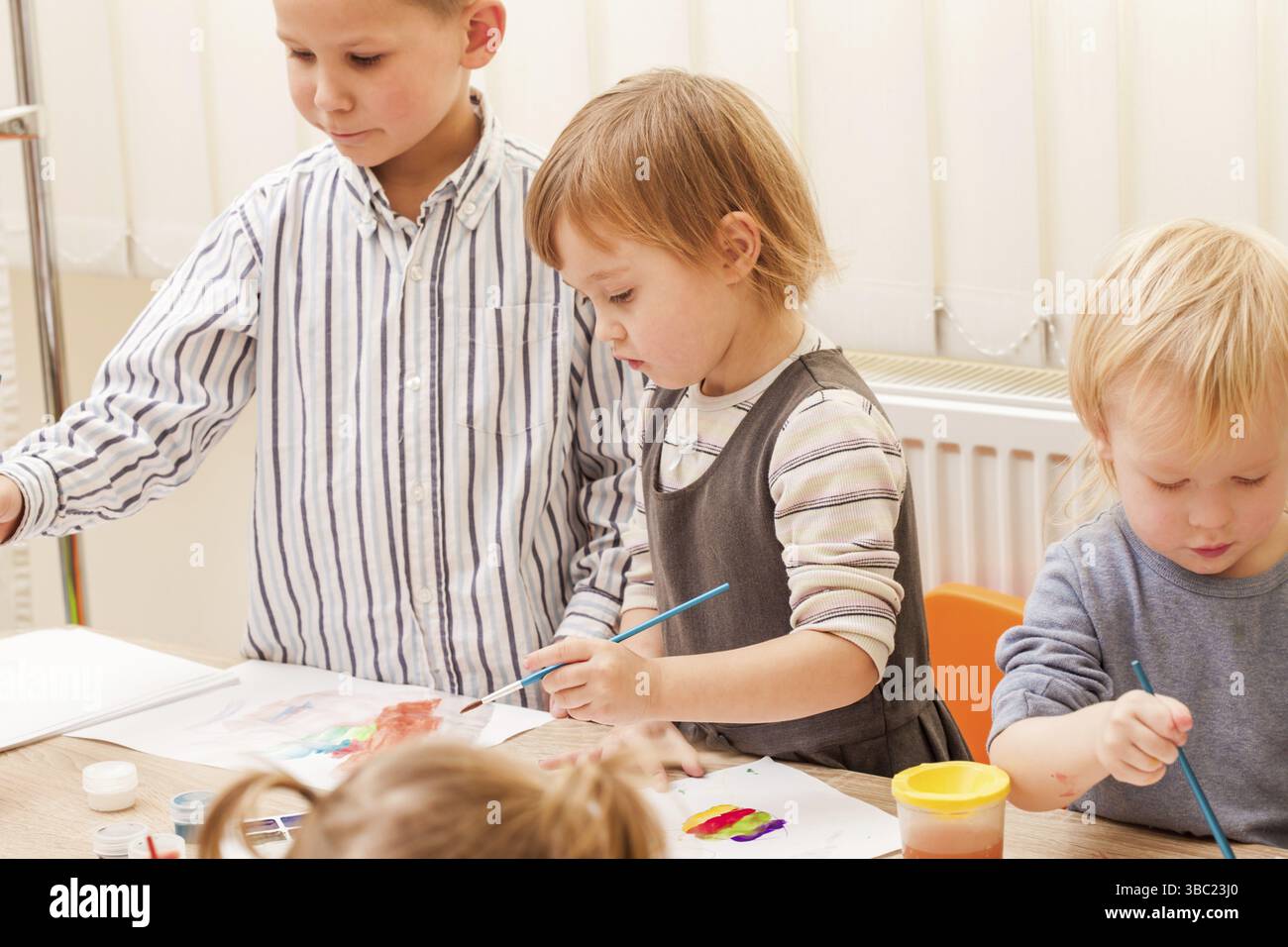 Children learn to paint with a brush and watercolors on paper in the ...