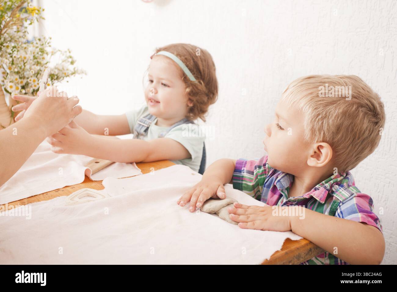 Little boy using a rolling pin that to roll modelling clay Stock Photo ...