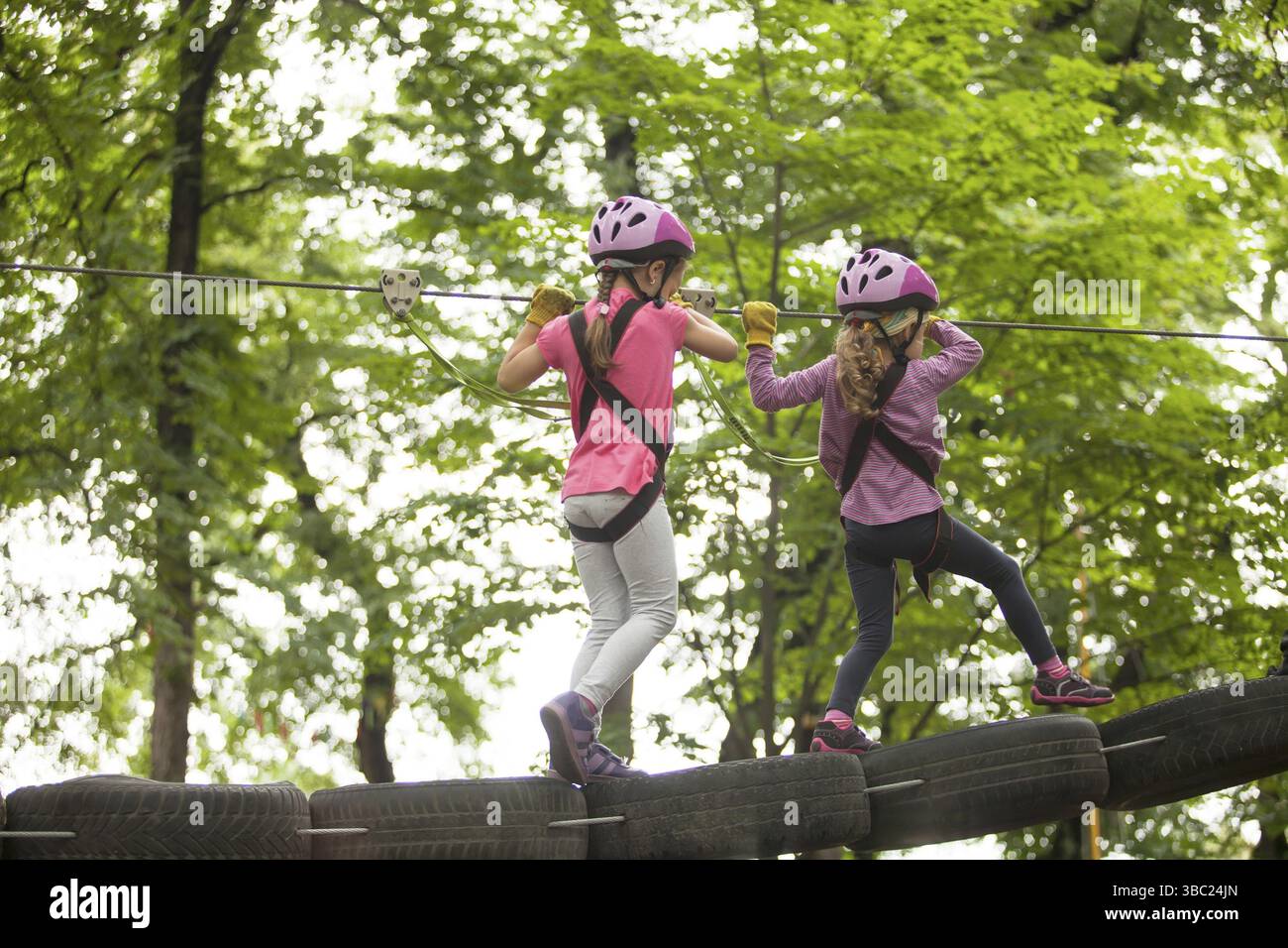 Kids on obstacle course in adventure park in mountain helmet and safety ...