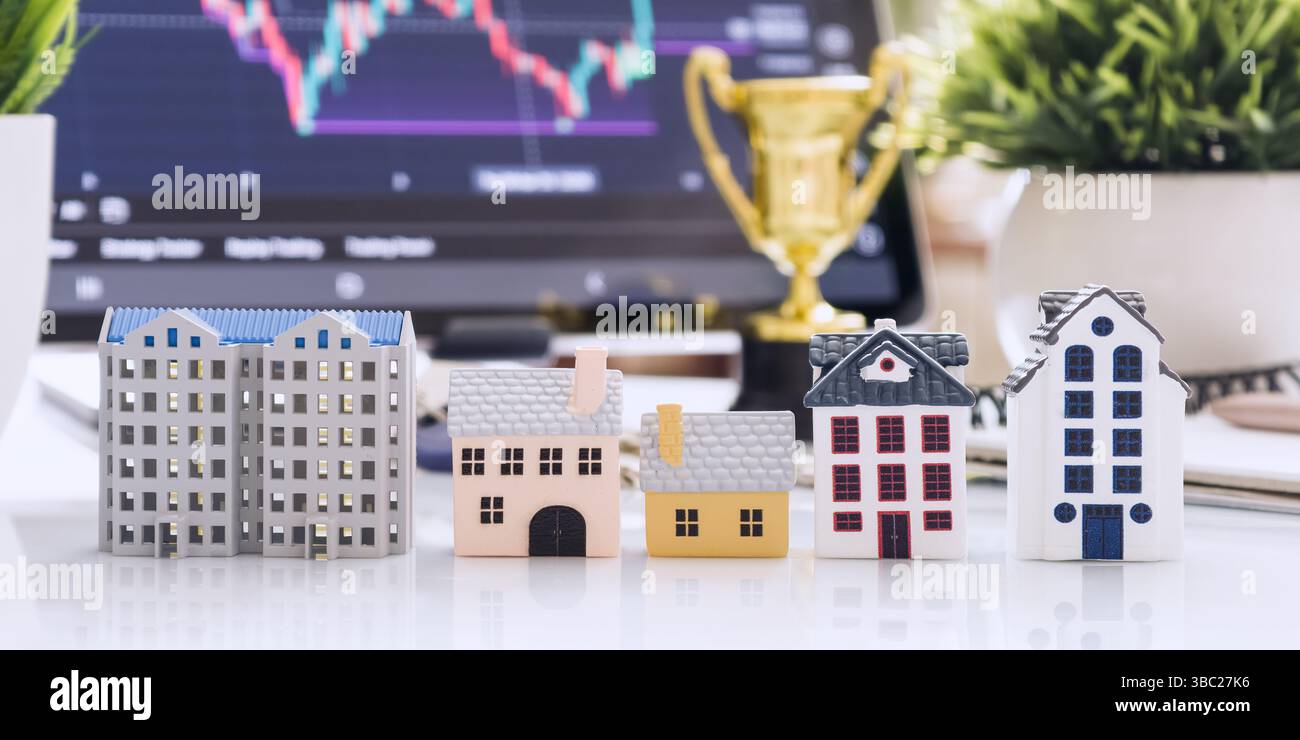 Various miniature house models displayed in front of a financial chart ...