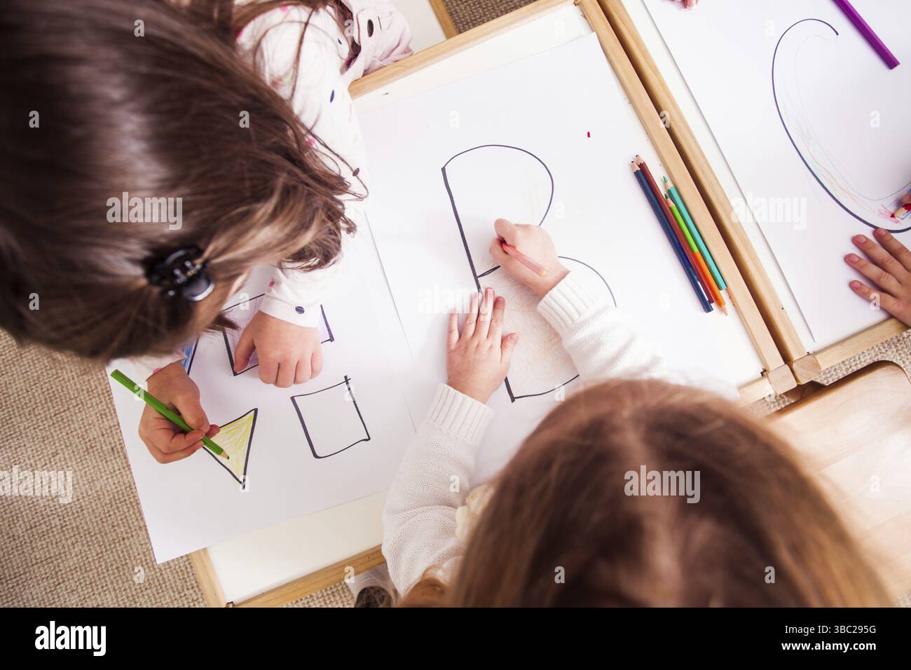 Overhead view of children in kindergarten learn letters and shapes ...