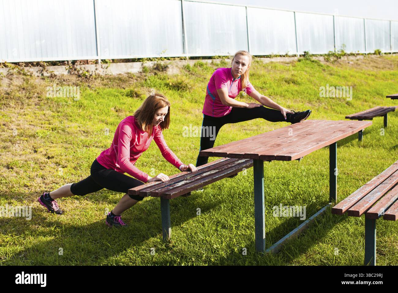 Two women doing gymnastics exercises outdoors before a workout Stock ...