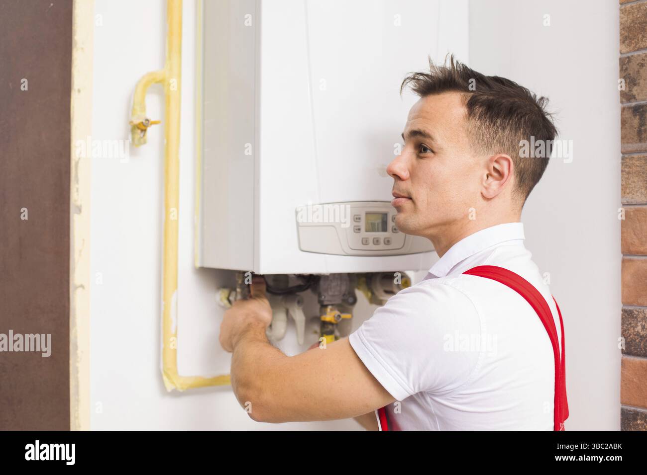 The side view of a young plumber installing a boiler Stock Photo - Alamy