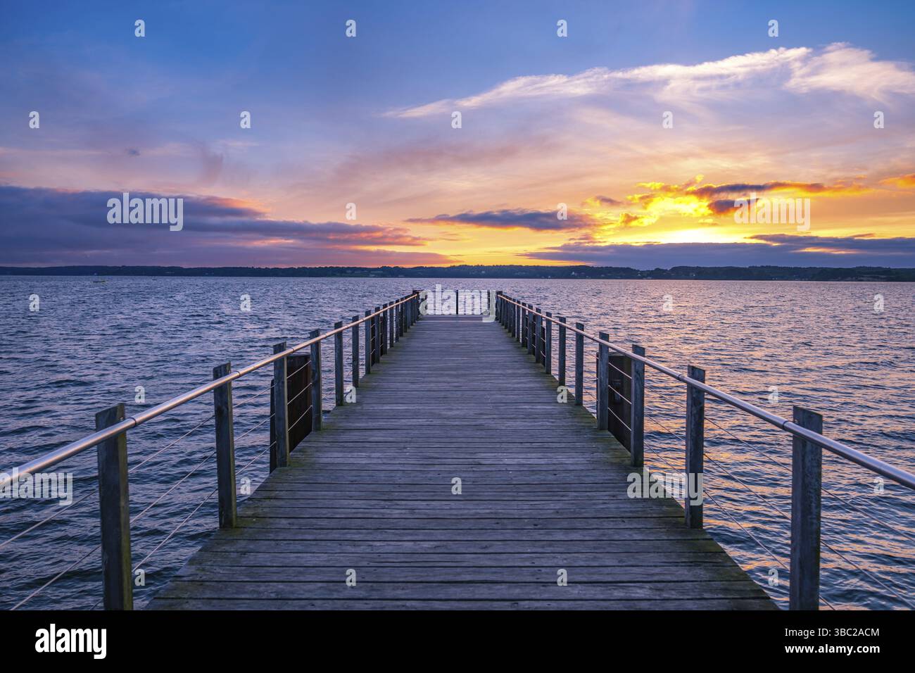 Long jetty stretches into the water at a peaceful sunset, Gluecksburg ...