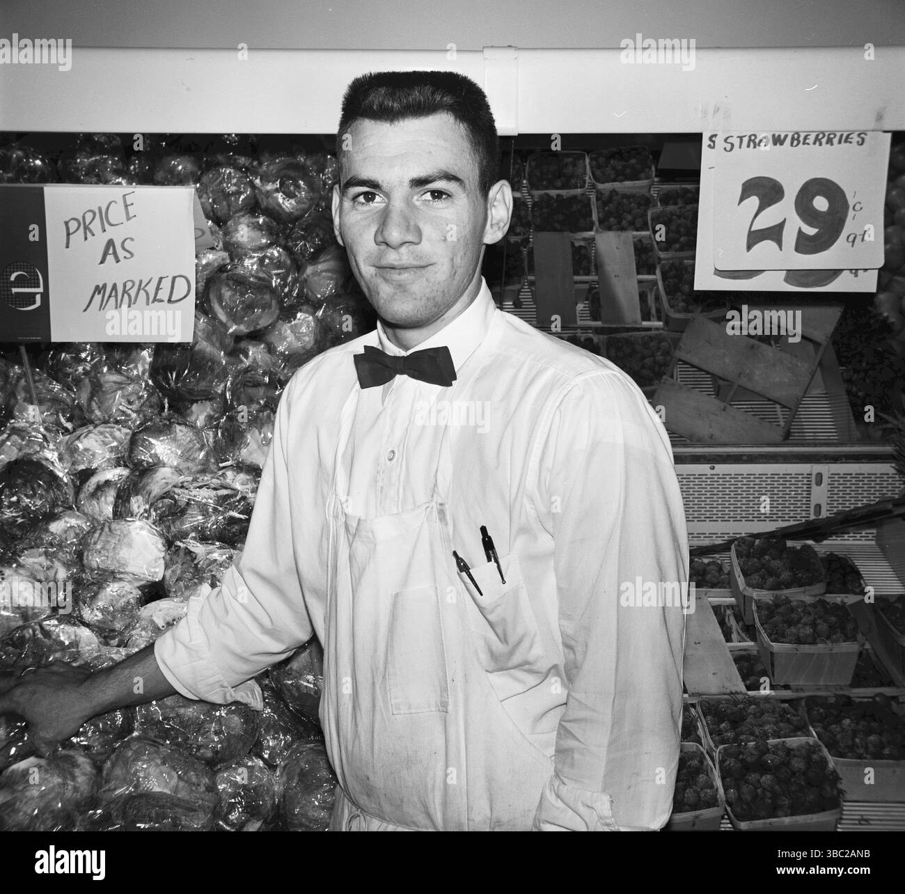 A worker poses in the produce section of small town grocery store, ca ...