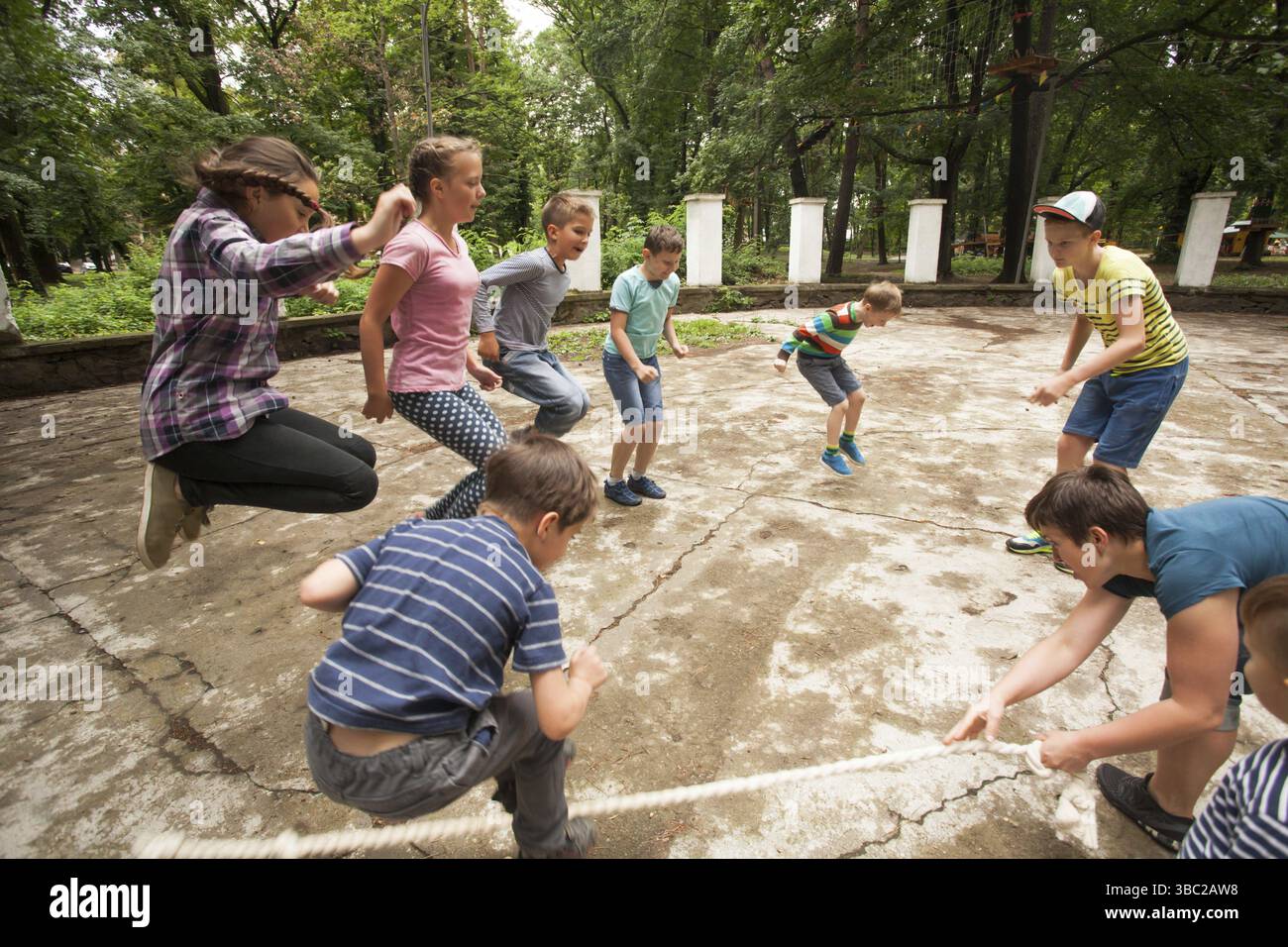 Children play outdoors jumping over the rope Stock Photo - Alamy