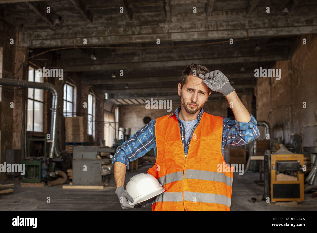 Portrait of young handsome engineer feeling tired after work, standing ...
