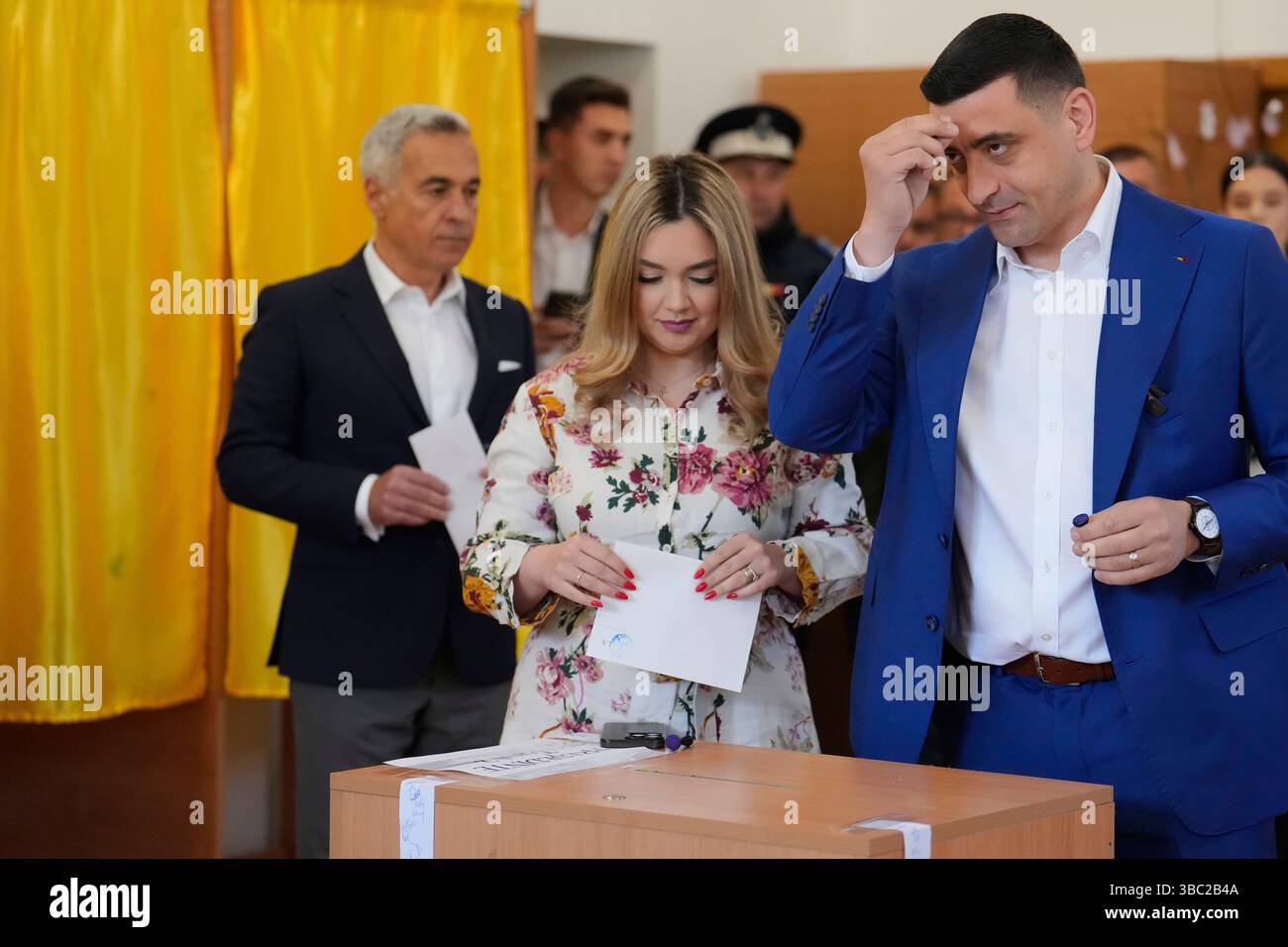 Presidential candidate George Simion casts his vote next to his wife ...