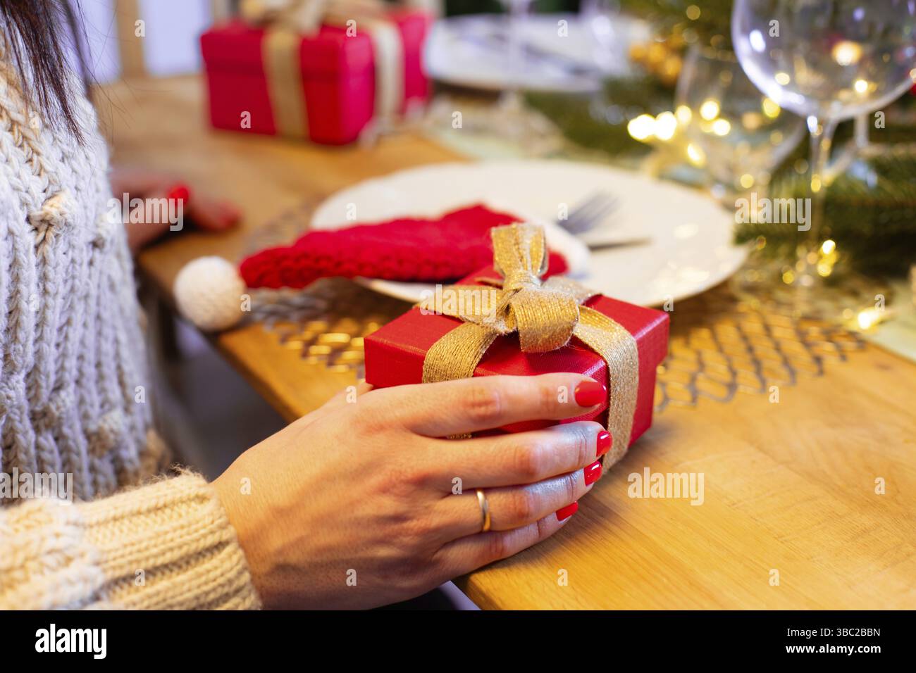 Small red gift box in woman's hands, closeup. Beautifule table setting ...