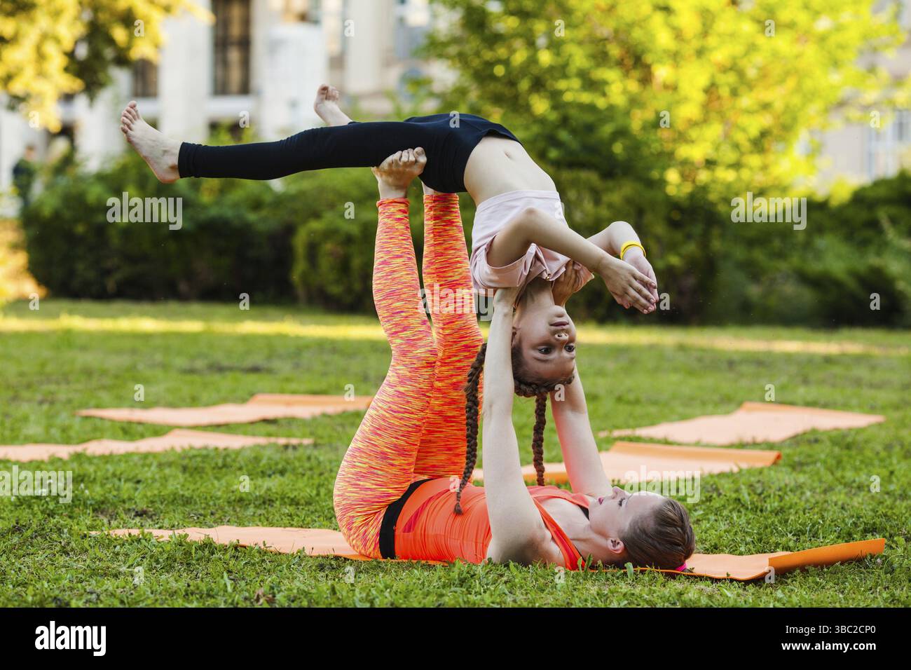The young woman holds on her feet a girl, performing an acrobatic trick ...