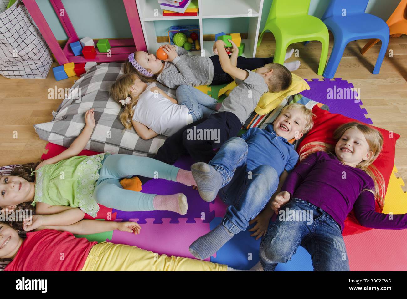 Top view cheerful and active kids laying on floor, covered with many ...
