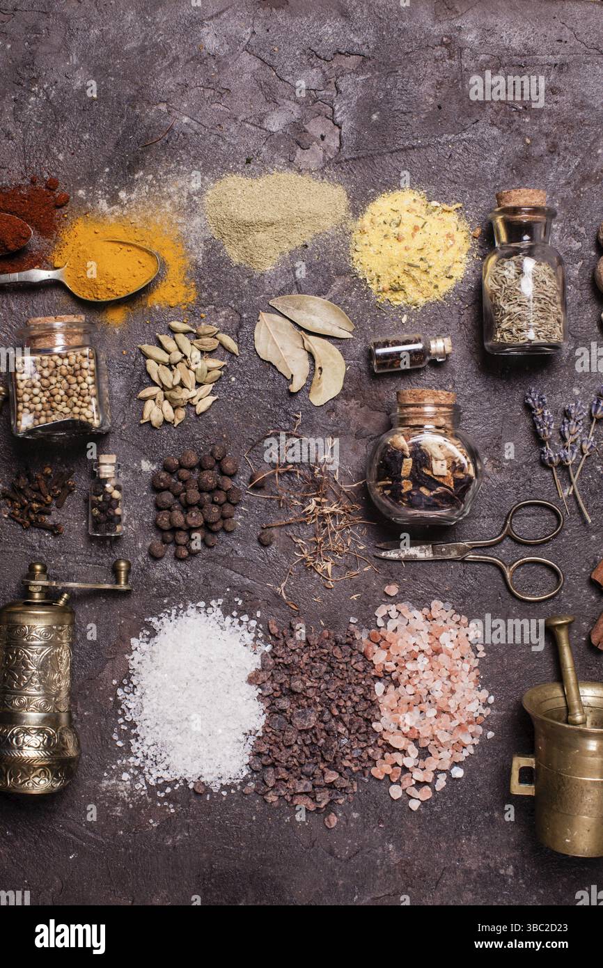 Flat lay composition of various spices and mortars over brown slate ...