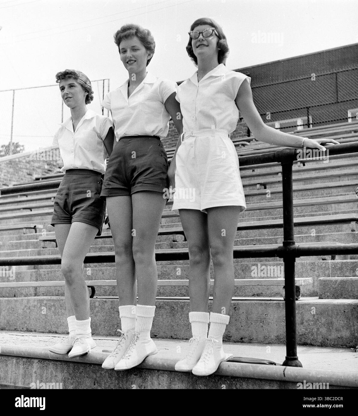 Three high school girls are shown in the football stands, ca. 1962 ...