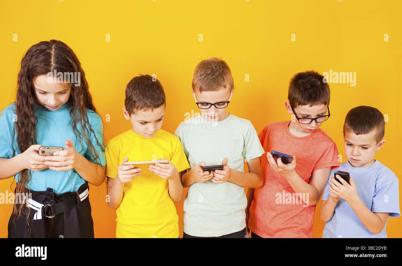 Group of kids using digital mobile phone over yellow background Stock ...