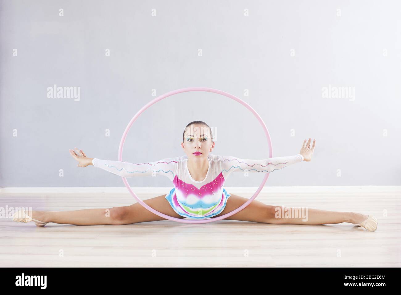 Portrait of flexible gymnast girl that doing acrobatic feat with pink ...