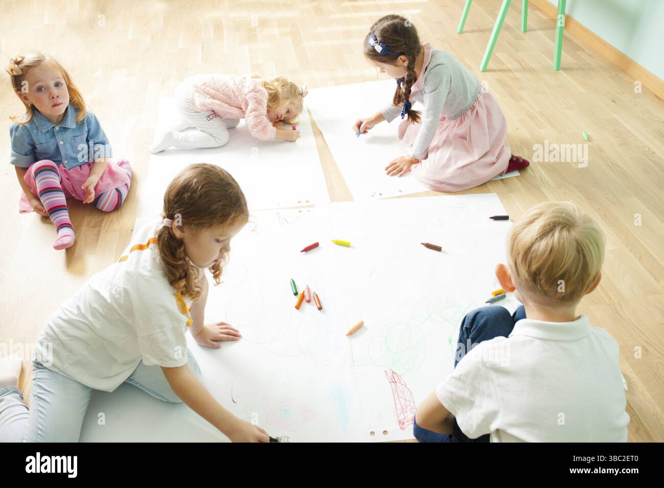 Top view of cute kids of different ages drawing on a floor in various ...