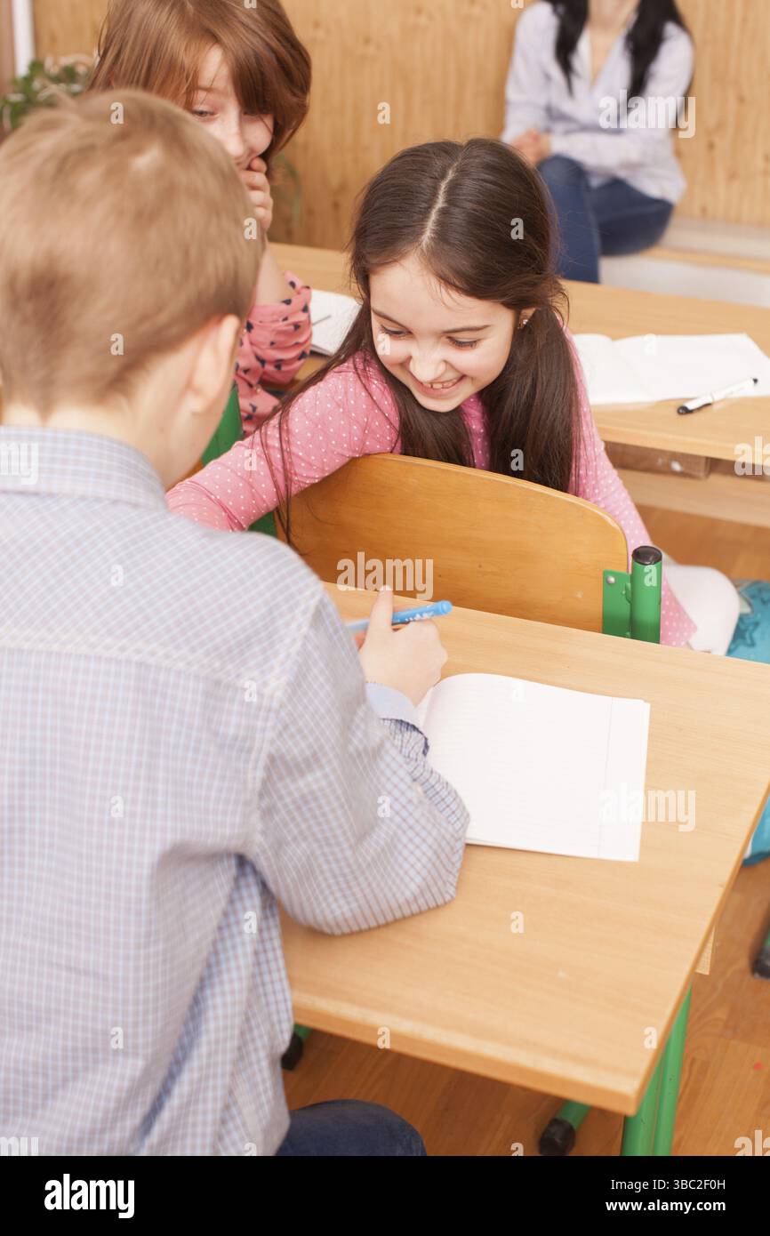Cute school girl helping her classmate during lesson Stock Photo - Alamy