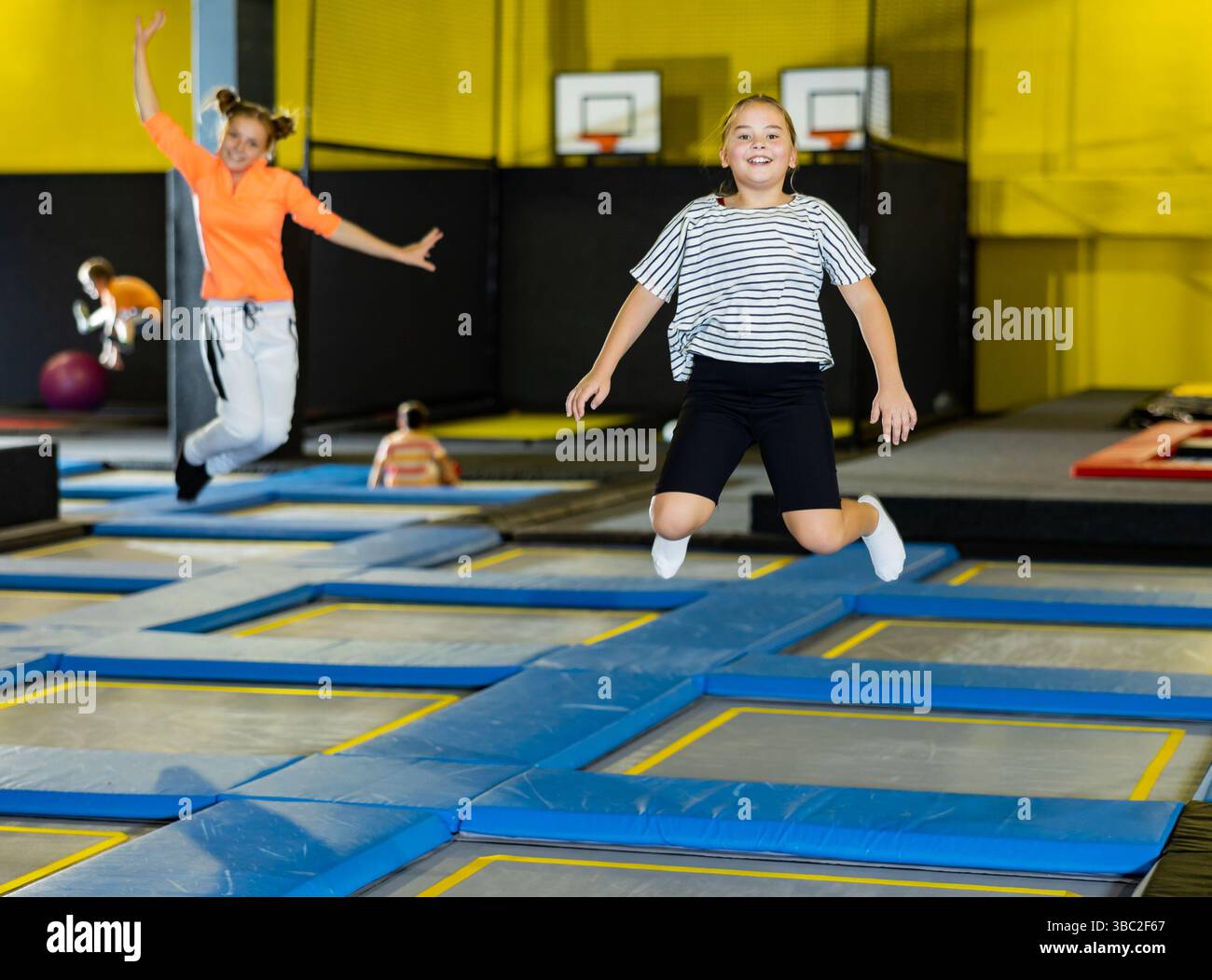 Emotional sporty preteen girl jumping on trampoline on indoor ...