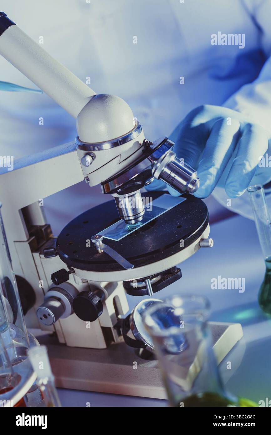 Man is looking into the ocular of microscope, doing reseach Stock Photo ...