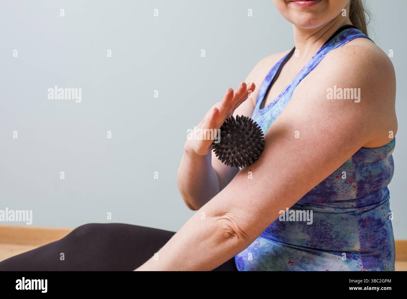 Closeup woman rolling myofascial ball on her arm to treat myofascial ...