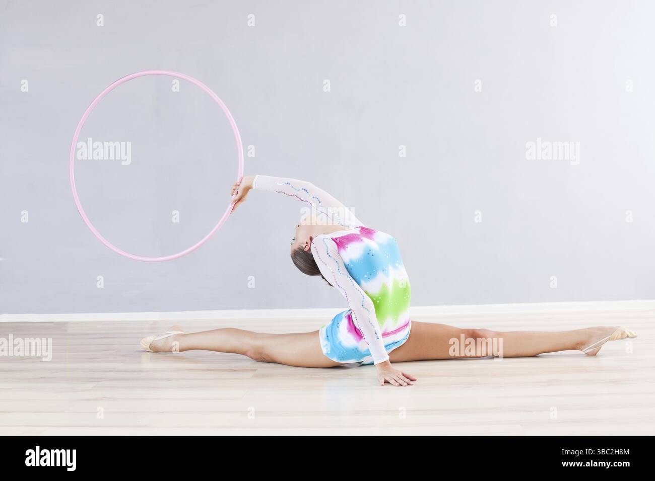 Portrait of flexible gymnast girl that doing acrobatic feat with pink ...