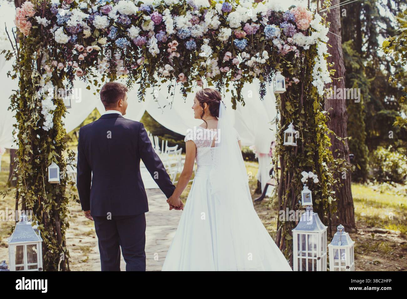 Beauty wedding couple under flower arch. Look from the back Stock Photo ...