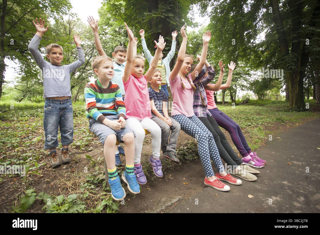 Group of positive children playing in the park sitting on the bench ...