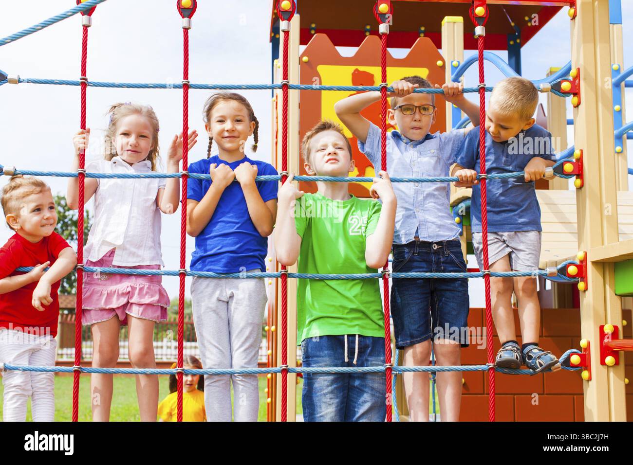 Six happy kids standing and holding the ropes of climbing net. Rope ...