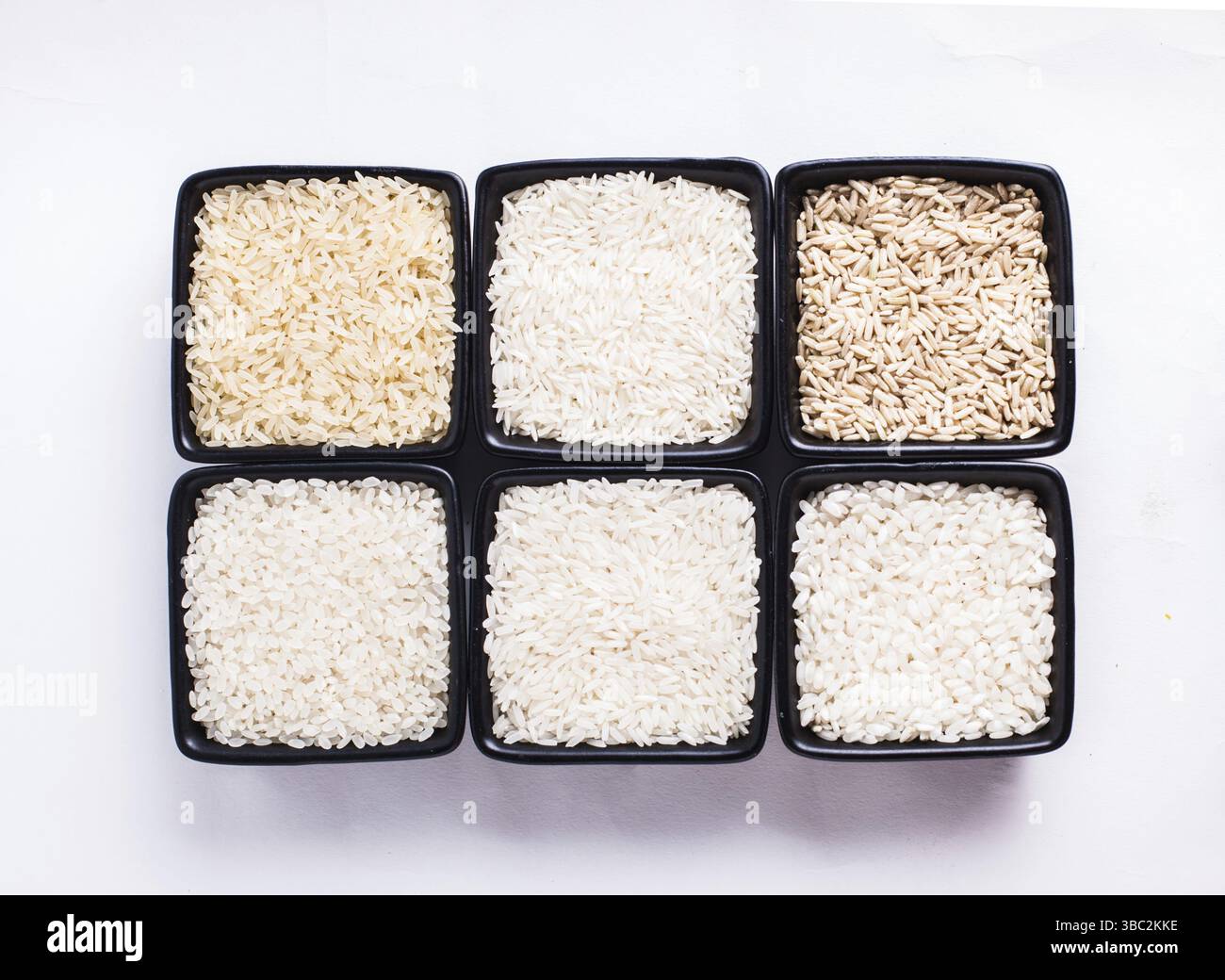 Various types of white and gray rice in black bowls on white Stock ...