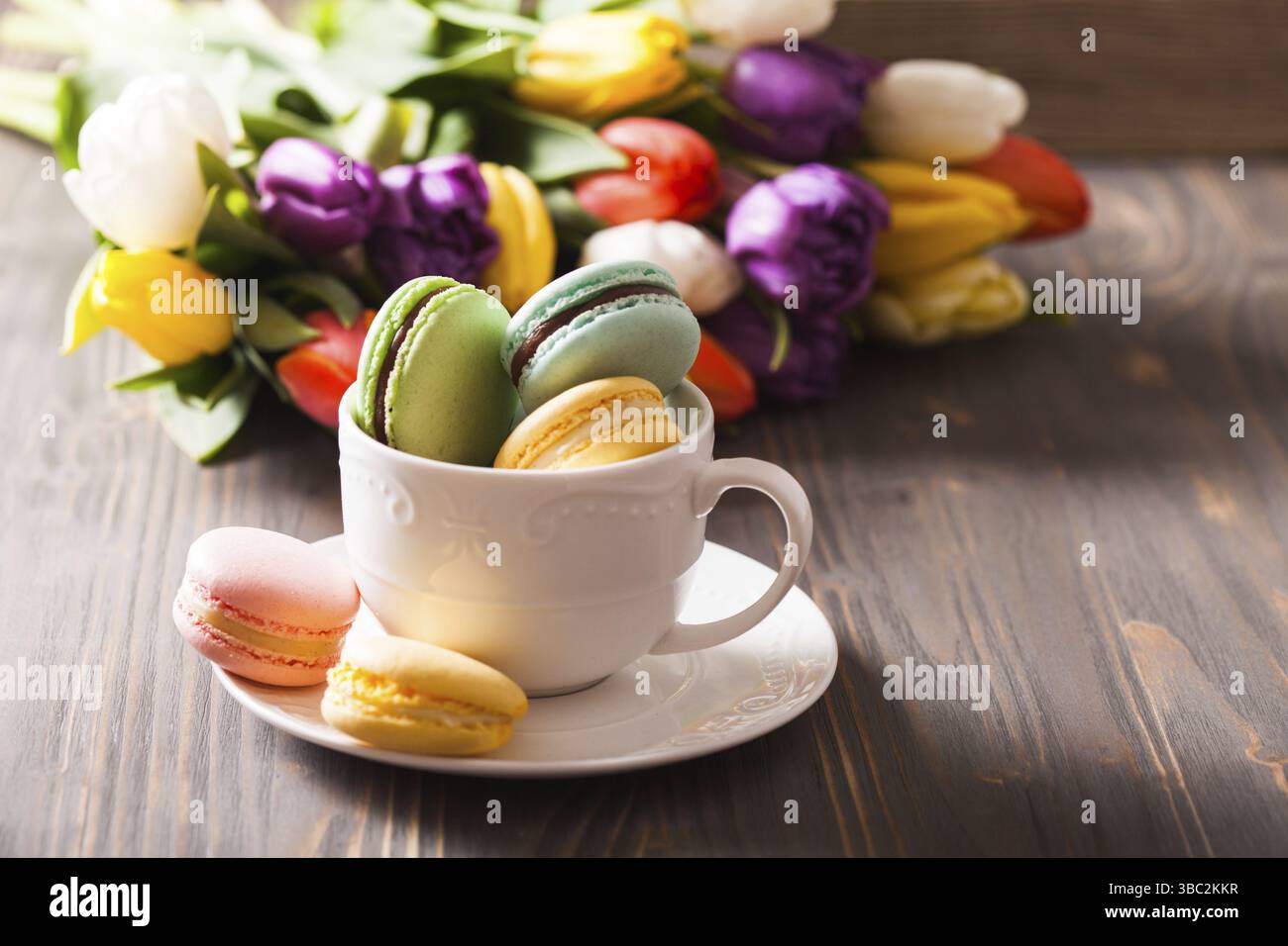 Color macaroons in a cup and flowers on the background Stock Photo - Alamy