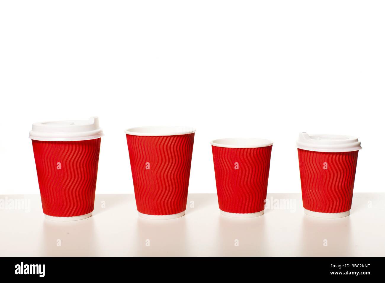Disposable red paper coffee cups of different sizes standing in a row ...