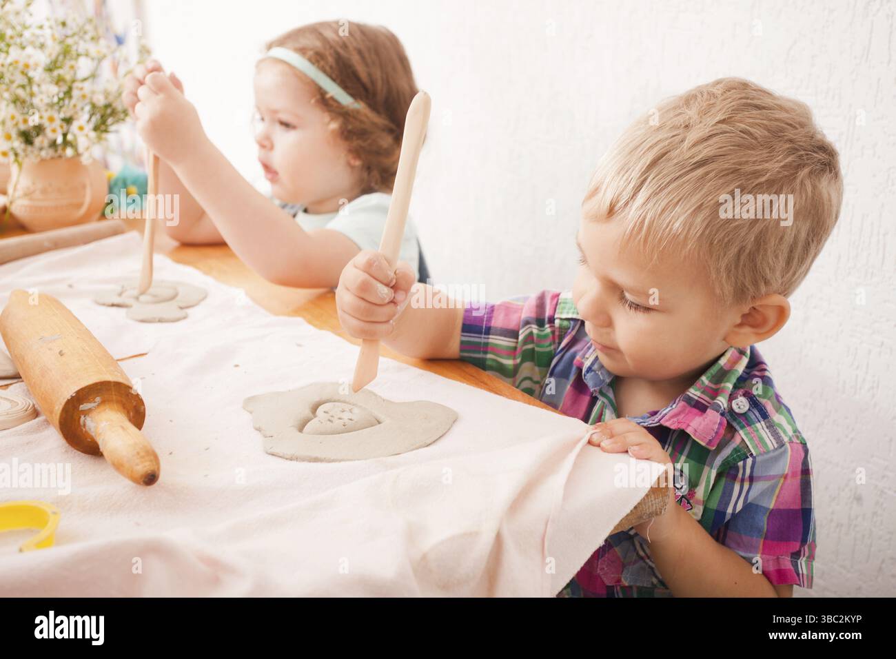 Little boy using a rolling pin that to roll modelling clay Stock Photo ...