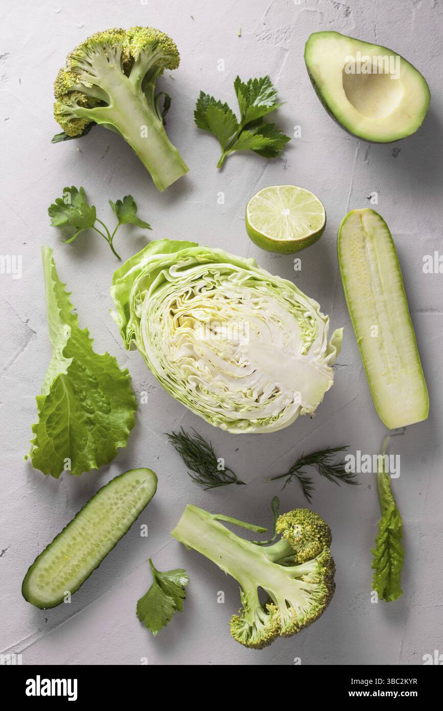 Composition of fresh green cut in half vegetables on a white background ...