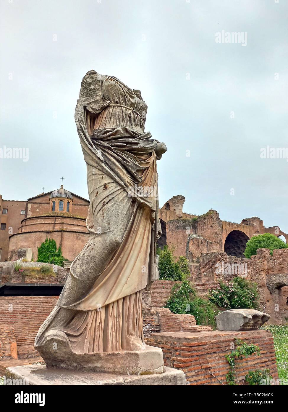 Rome, Lazio, Italy. April 15 2025. Ancient Roman statues without heads lined up in a grassy path ...