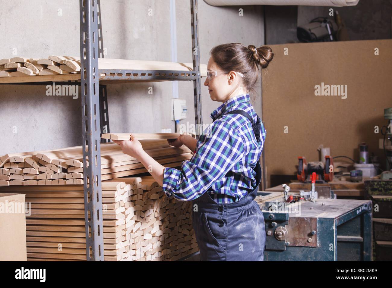 Portrait of professional female woodwork factory worker in overalls and ...