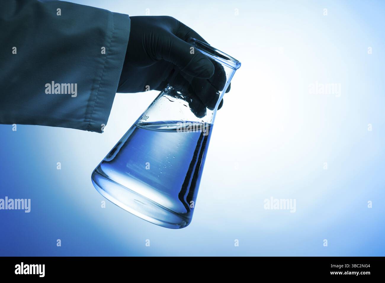 The conical flask with green liquid in the hand - laboratory glass ...