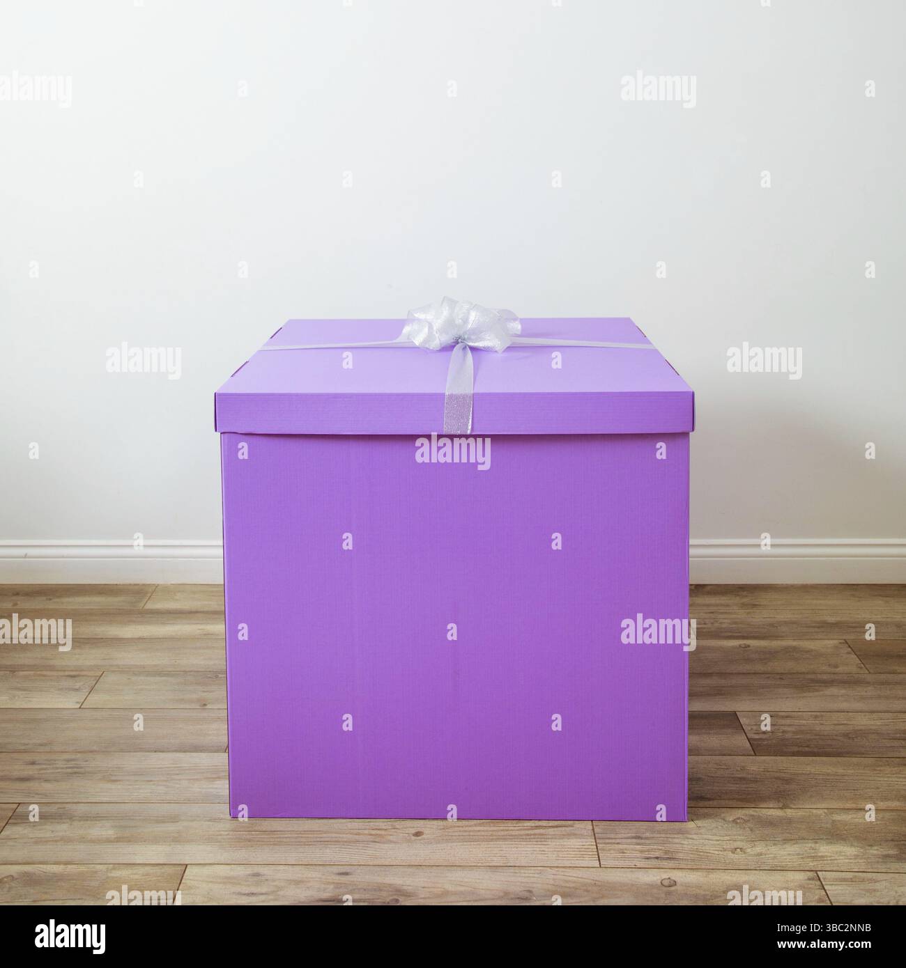 The big purple box with a white bow at the white wall background. The ...