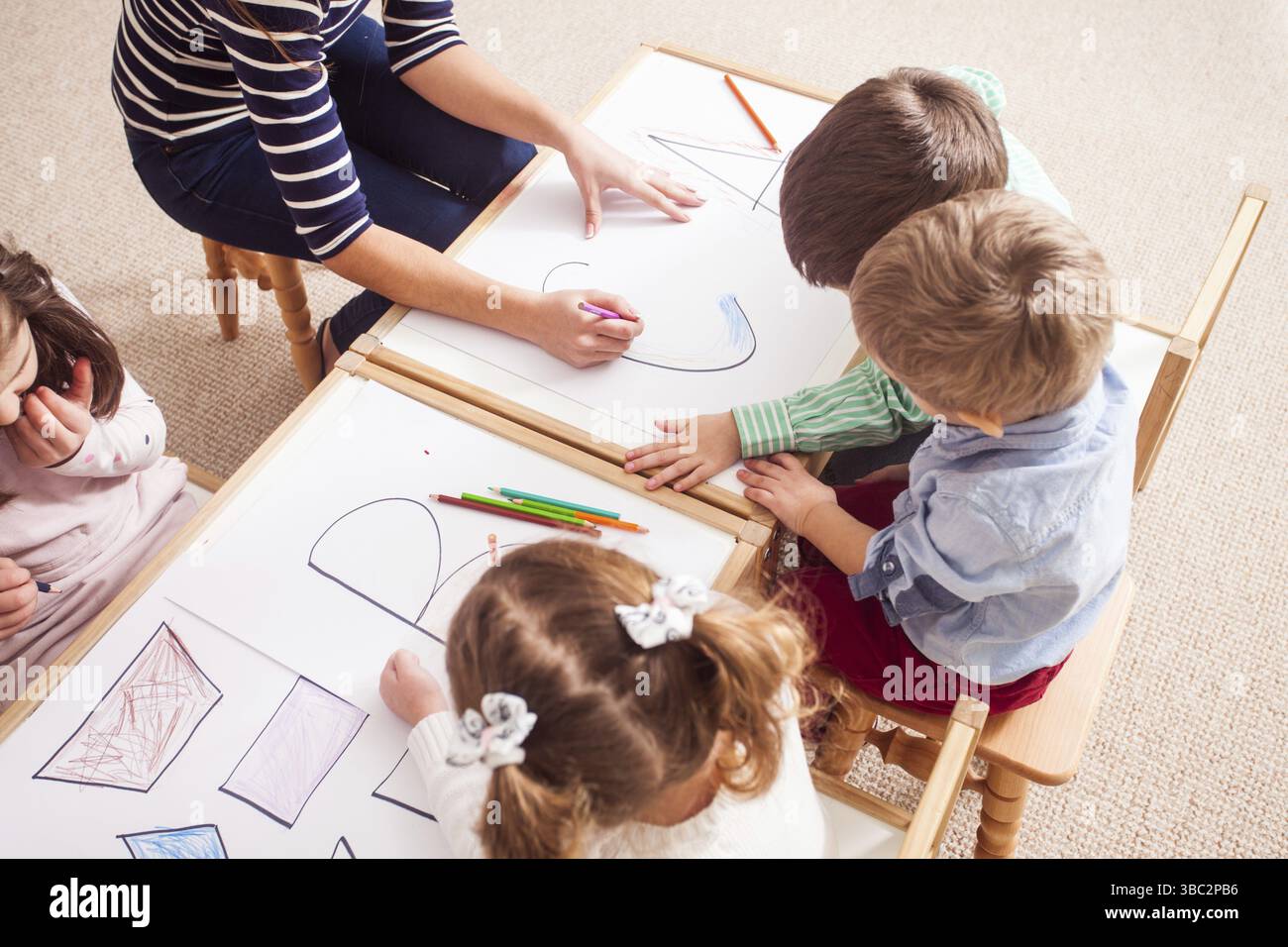 Overhead view of children in kindergarten learn letters and shapes ...