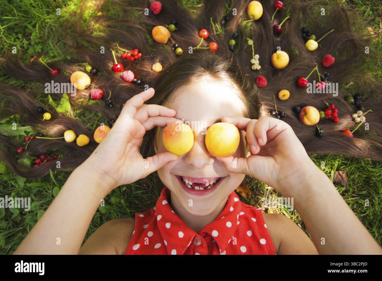 Seven years old girl have fun on the grass, apricots on the eyes Stock ...