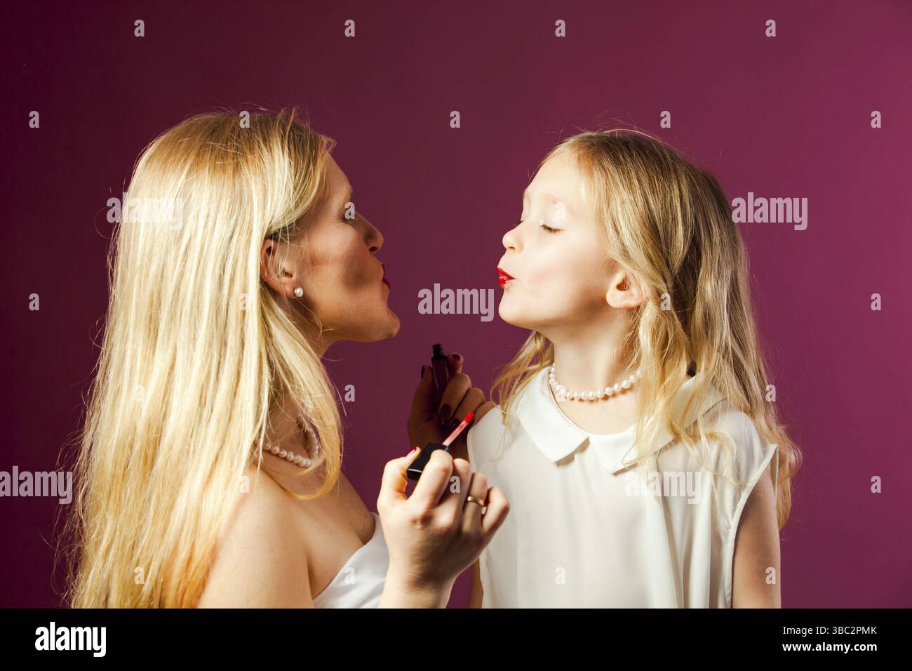 Close-up portrait of charming blond mother and daughter in studio ...