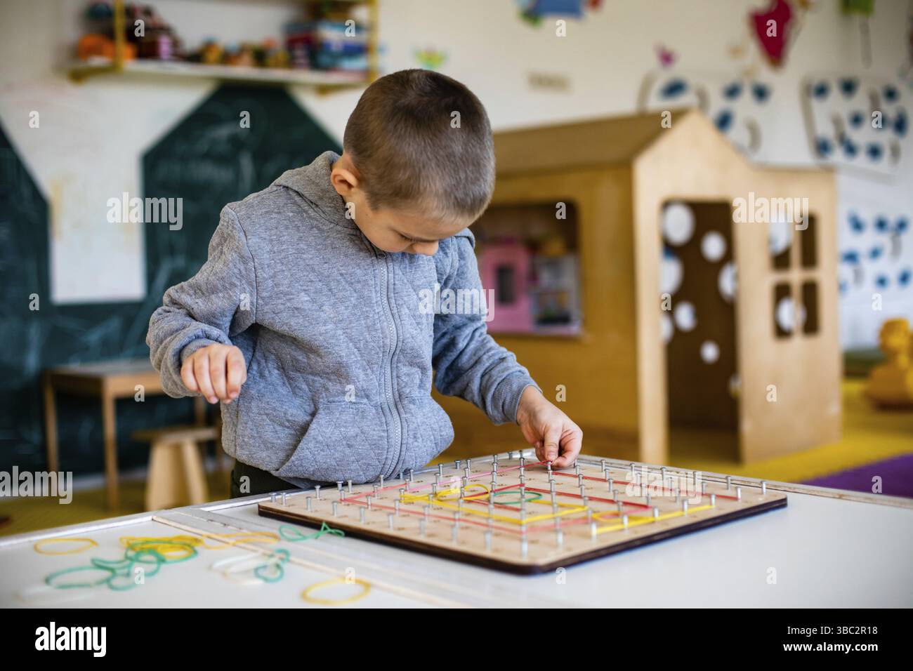 Lovely preschool boy exploring geoboard at daycare. Montessori games ...