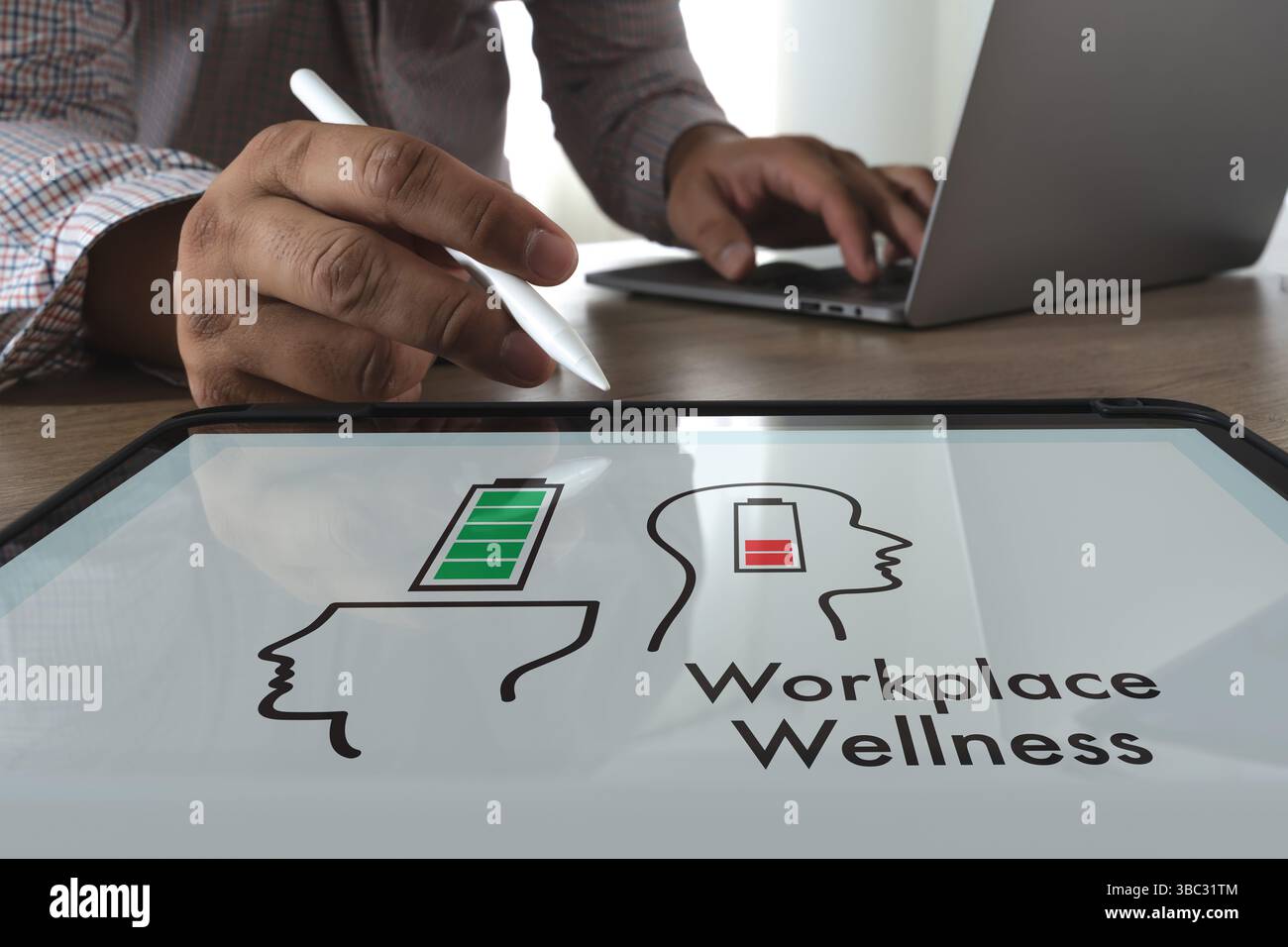 A wellness in the workplace image shows person working digital tablet ...