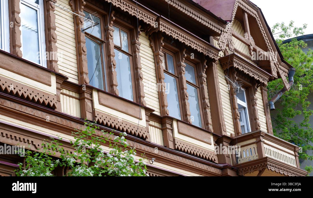 Vintage brown wooden building in a modern city. Traditional Russian architecture, wooden windows ...