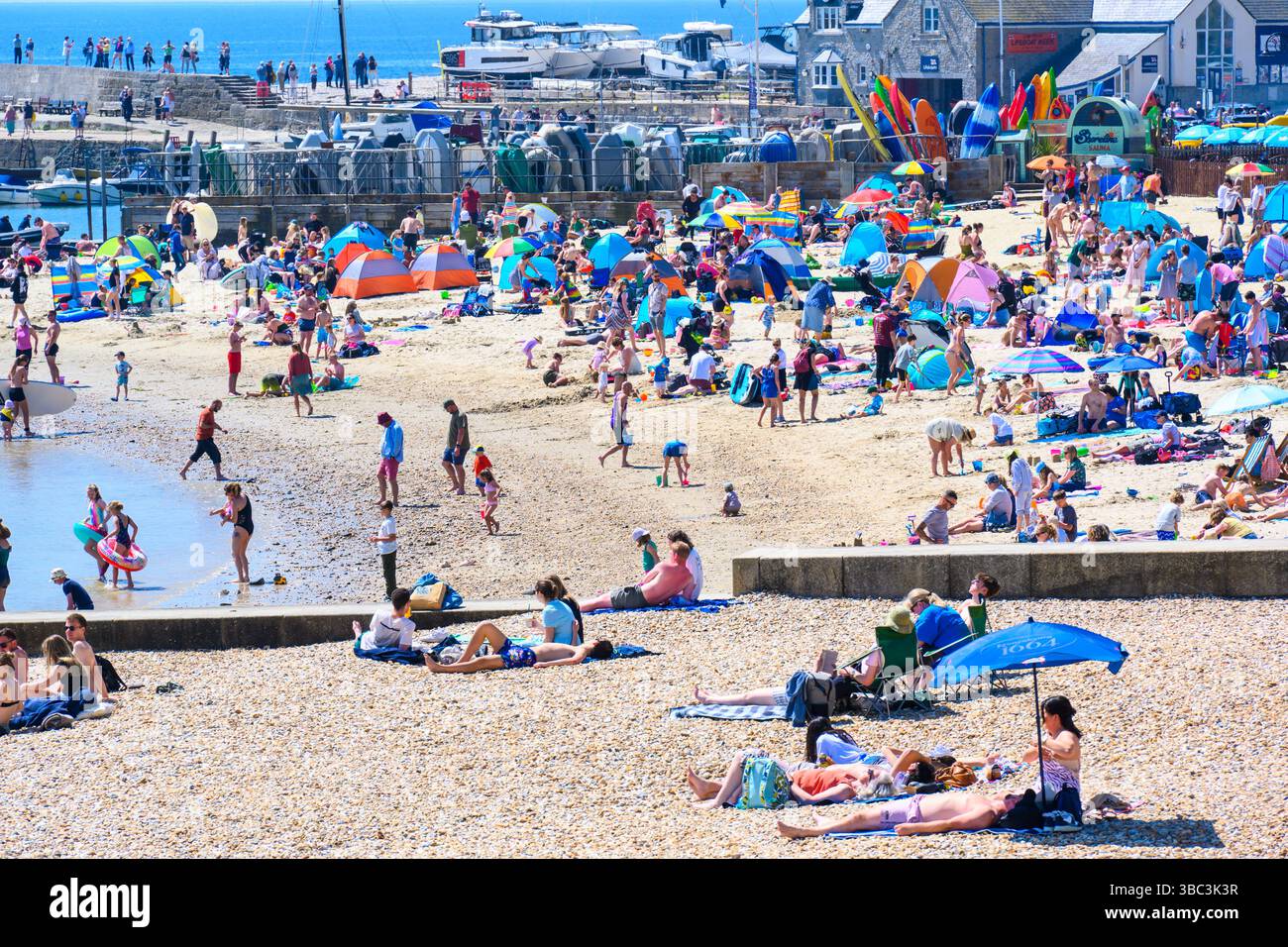 Lyme Regis, Dorset, UK. 18th May, 2025. UK Weather. Sunbathers flock to ...