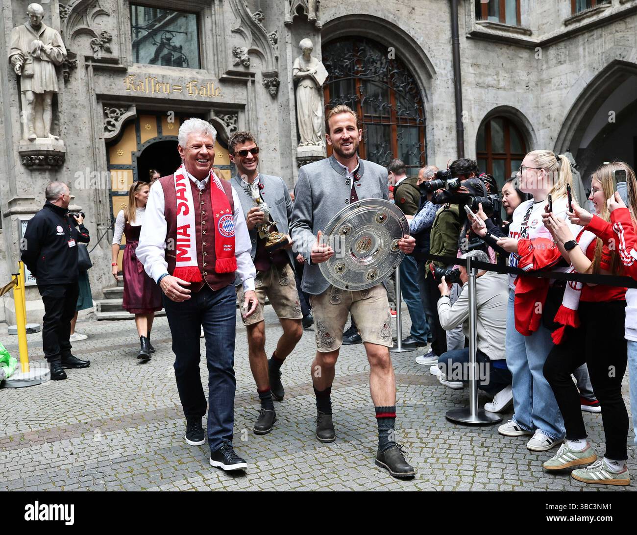 Bayern's Harry Kane, right, arrives with the Championship trophy ...