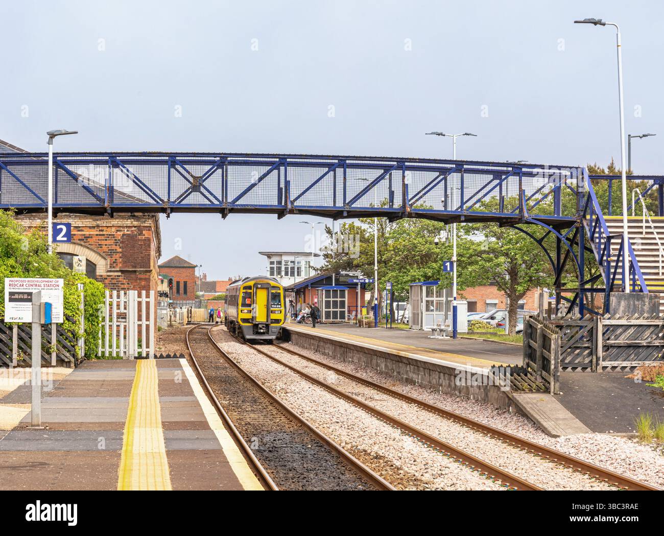 A locomotive and carriages arrive at a small railway station. A hazy ...