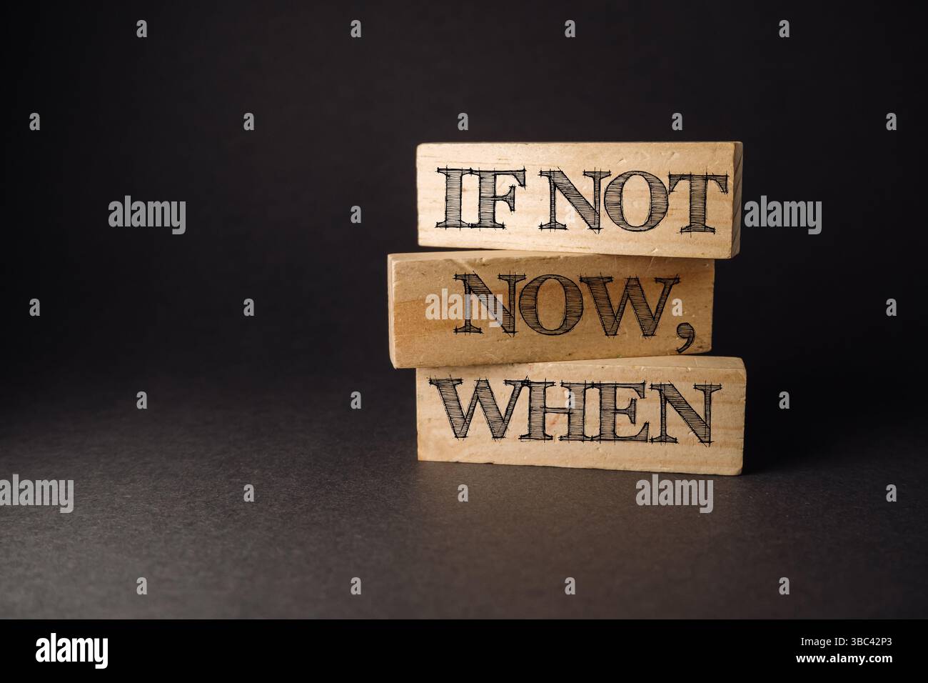 Three wooden blocks with the words if not now when written on them. The ...